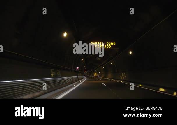 Point of view shot driving through an illuminated highway tunnel at ...