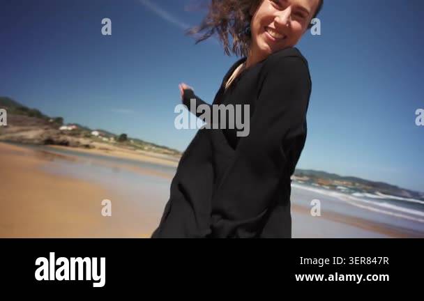 A happy young woman in a black dress runs, dances, and spins joyfully ...