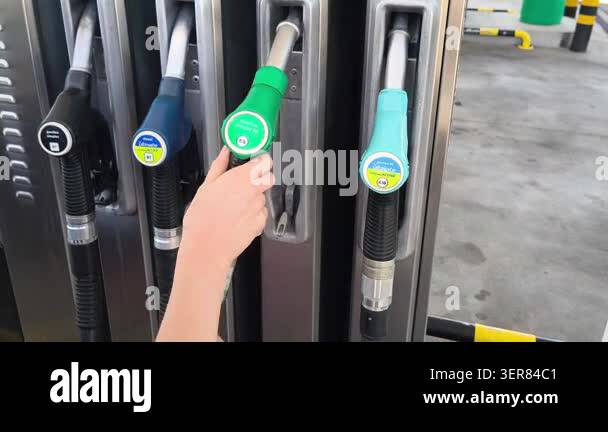 Hand selects a gasoline nozzle at a fuel station pump preparing for ...