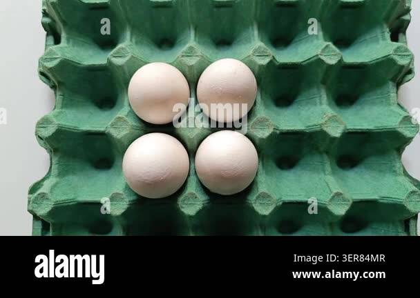 Top down studio view of four smooth white raw chicken eggs resting in ...