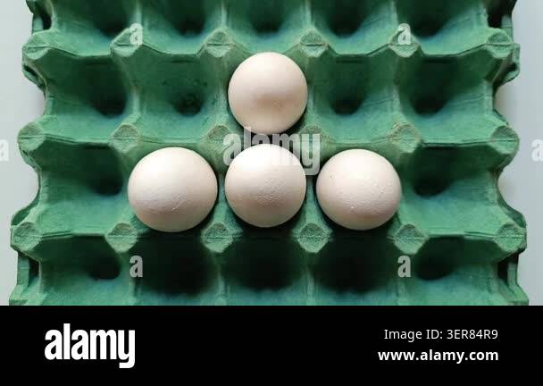 Top down studio view of four smooth white raw chicken eggs arranged in ...