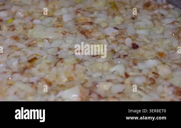 Close up shot of finely chopped white onions frying and sauting in oil ...
