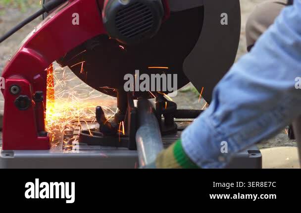 Close-up view of a metal chop saw cutting a steel pipe, generating ...