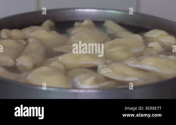 Close-up shot of delicious homemade dumplings boiling in a large metal ...