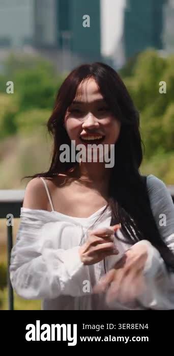 Happy young woman dancing and smiling at the camera for a social media ...