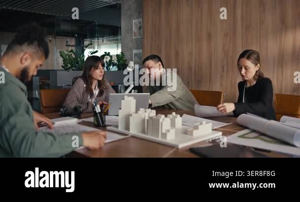 Group of architects shares ideas about a building project with models ...