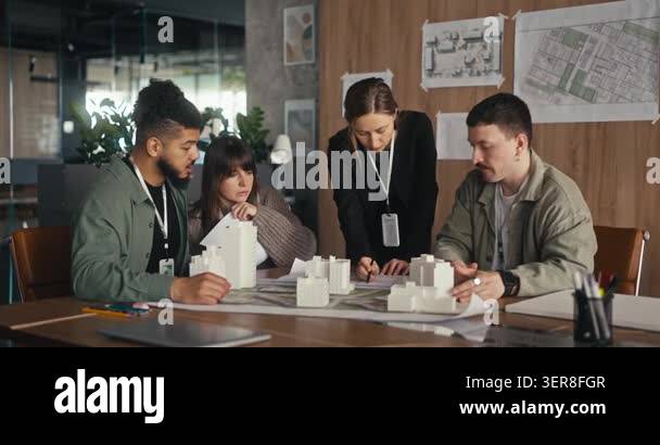 Team members gather around a table to review project models and share ...