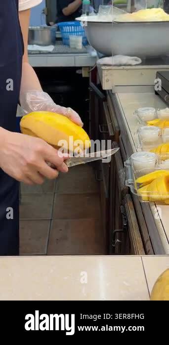 Close up of street vendor hands peeling a fresh ripe yellow mango for ...