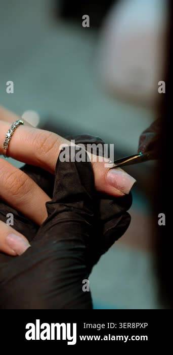 Close-up of nail technician trimming cuticle with manicure scissors ...