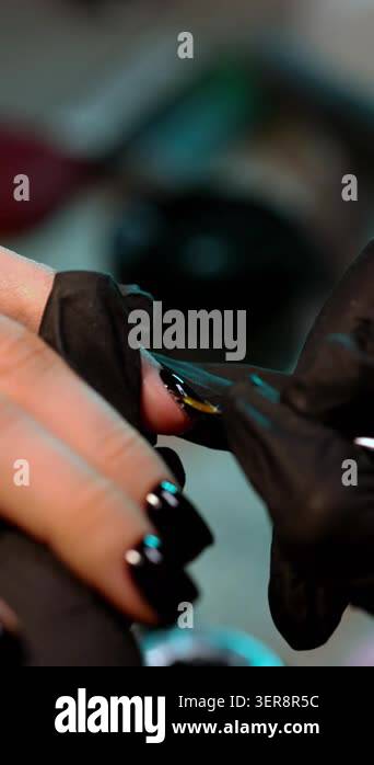 Close-up of nail technician applying transparent top coat over colored ...