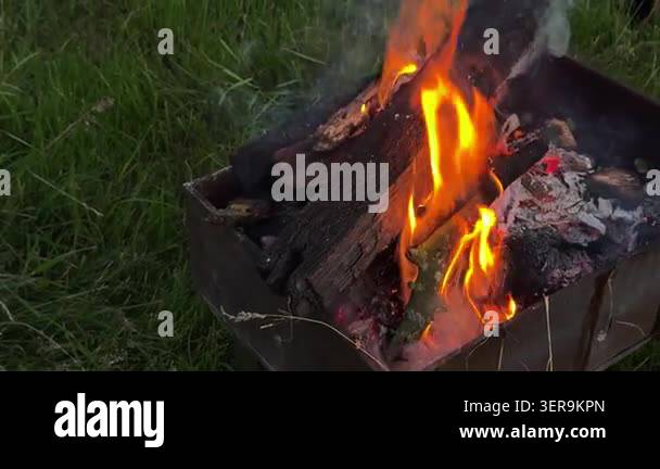 Close up of crackling fire in outdoor barbecue grill at dusk. Cozy ...