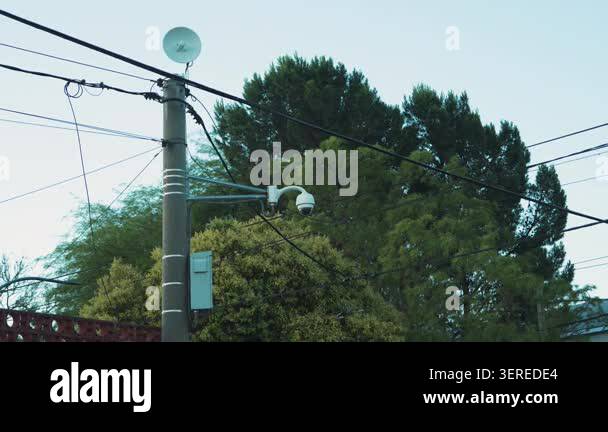 Urban security camera installed on concrete pole surrounded by overhead ...