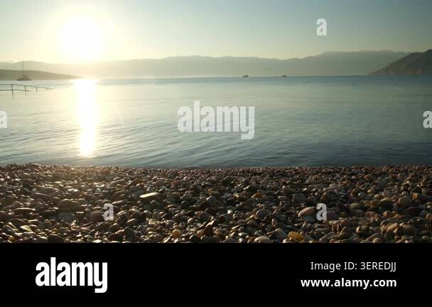 Calm lake sunrise with rocky shore and mountains Croatia Krk Stock ...