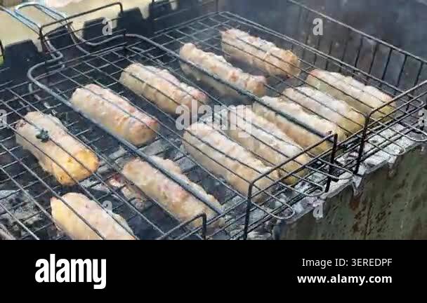 Golden crispy bacon around sausages slowly roasting over hot coals in ...