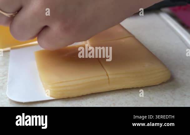Hands placing sliced hard cheese cubes onto disposable plate during ...