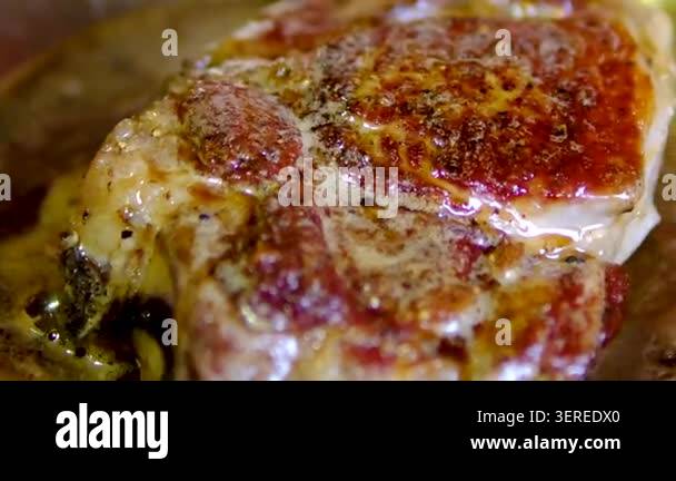 Chef in black gloves seasons, sears and bastes a ribeye steak with ...