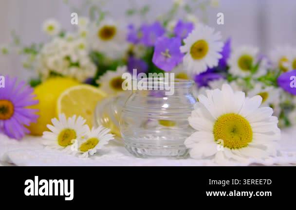 Clear empty glass jar placed among chamomile blossoms and colorful ...
