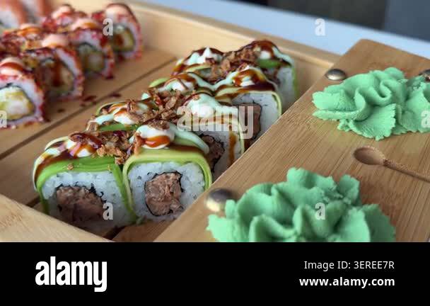 Fresh sushi rolls wrapped with avocado and topped with creamy sauce ...