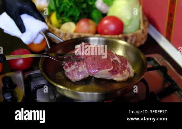 Chef in black gloves seasons, sears and bastes a ribeye steak with ...