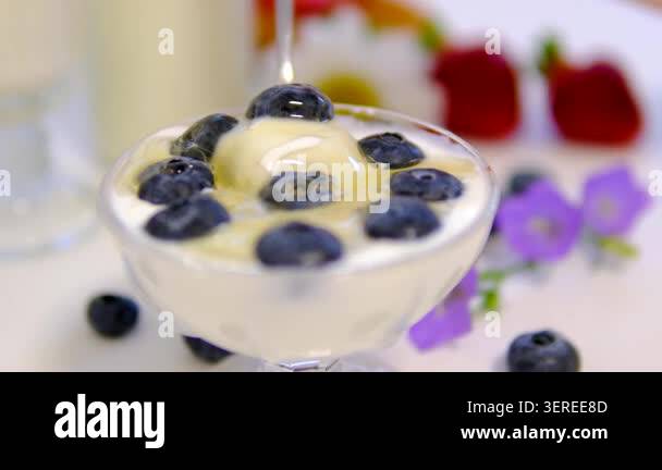 Creamy yogurt is poured into a glass bowl, topped with fresh ...