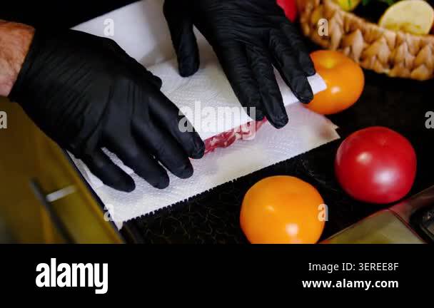 Chef in black gloves seasons, sears and bastes a ribeye steak with ...
