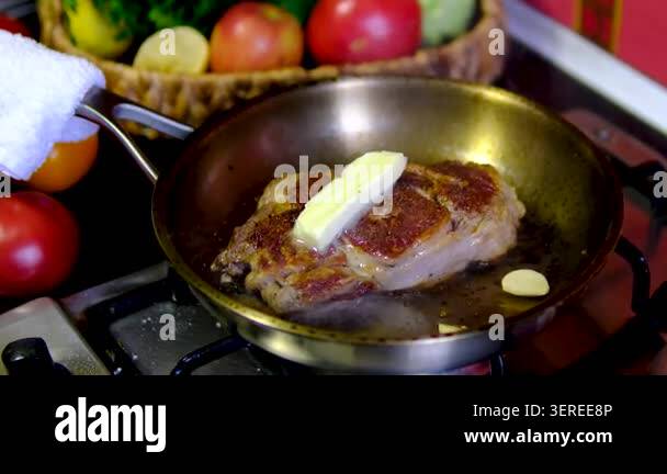 Chef in black gloves seasons, sears and bastes a ribeye steak with ...