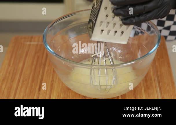 The chef is grating cheese in a glass bowl while cooking omelet Stock ...