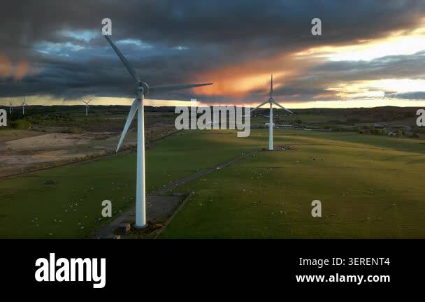 Drone footage flying between wind turbines over green farmland with ...