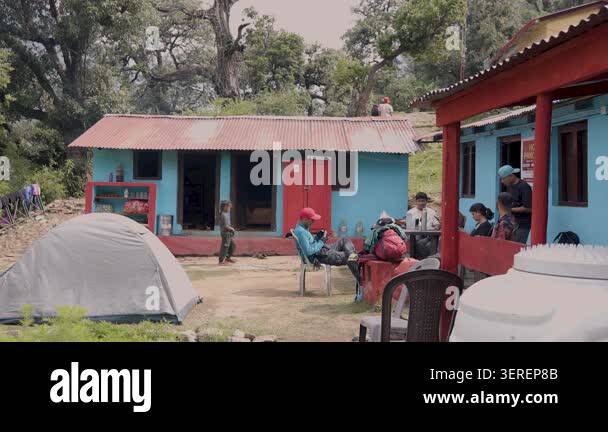 Trekkers relaxing outside a traditional blue and red mountain lodge ...