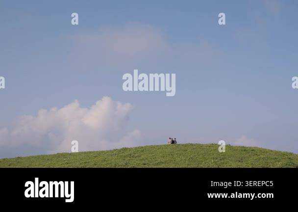 A lone trekker walks along a grassy ridge with the towering Chaukhamba ...