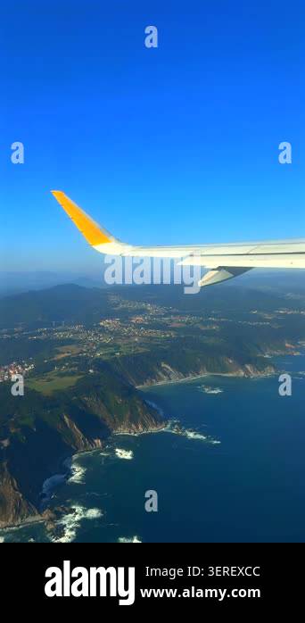 View of an airplane wing over a dramatic coastal landscape during ...