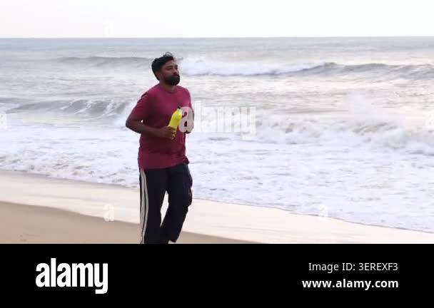 Bearded Man Jogging on Beach with Yellow Water Bottle for Summer ...
