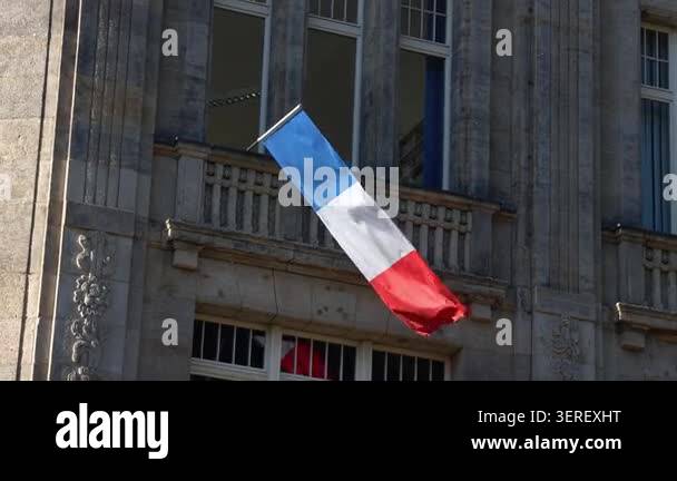 French flag waving from a historic building's balcony, showcasing ...