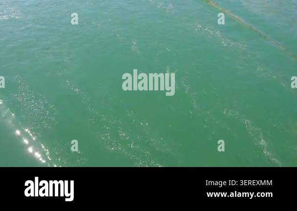 Turquoise water surface displays gentle ripples and sunlight ...