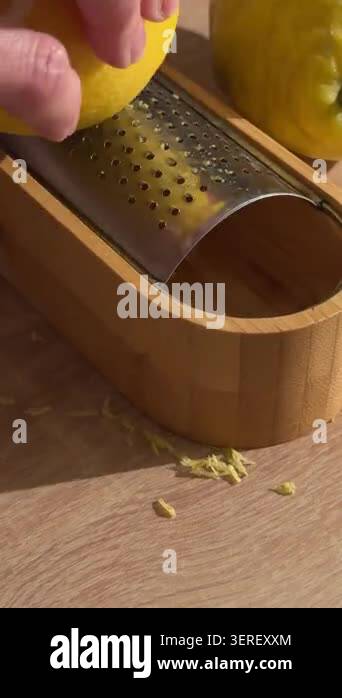 Close up of a person's hand grating fresh lemon zest for cooking or ...