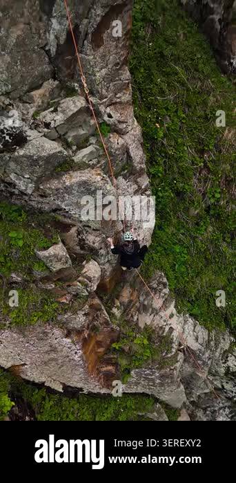 Vertical video Aerial drone shot of man athlete is climbing on the high ...