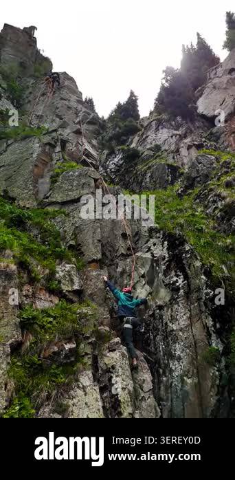 Vertical video Aerial drone shot of man athlete is climbing on the high ...