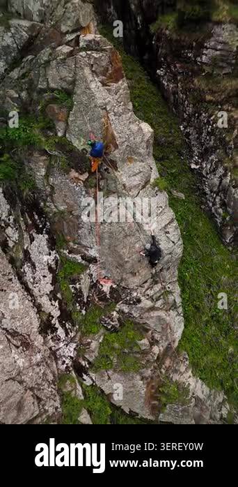Vertical video Aerial drone shot of man athlete is climbing on the high ...