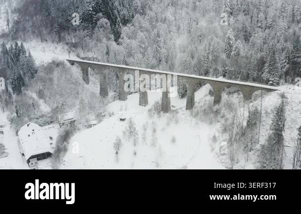 Cinematic drone flight moving towards a historic stone viaduct crossing ...