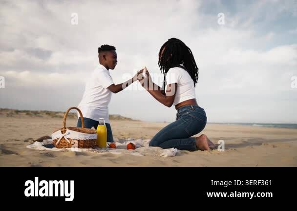 African American mother and son enjoying a seaside picnic on sandy ...