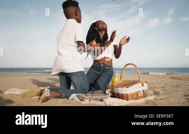 African American mother and son enjoying a seaside picnic on sandy ...