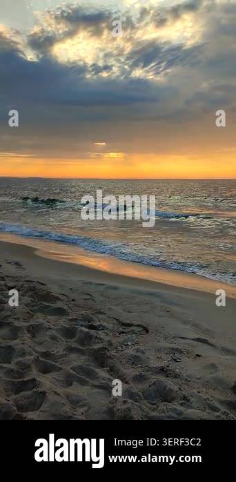 Sea waves with blue water on sand of seashore on sunset and sunrise ...