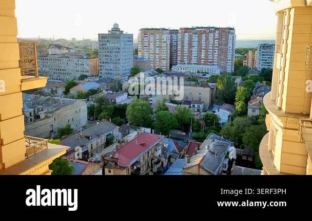 Cityscape. Old buildings with roofs, green trees, road and moving cars ...