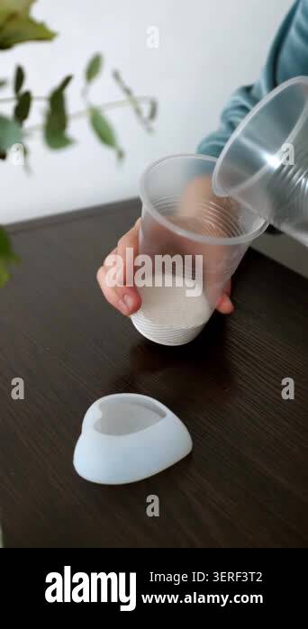 Hands pouring water from a cup into gypsum powder to mix plaster ...