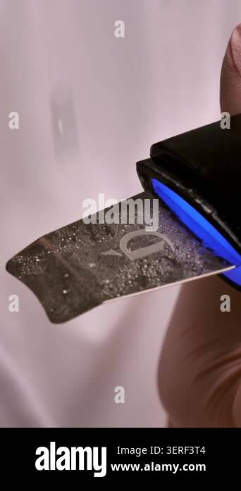 Close-up of an ultrasonic skin scrubber spatula with water droplets and ...
