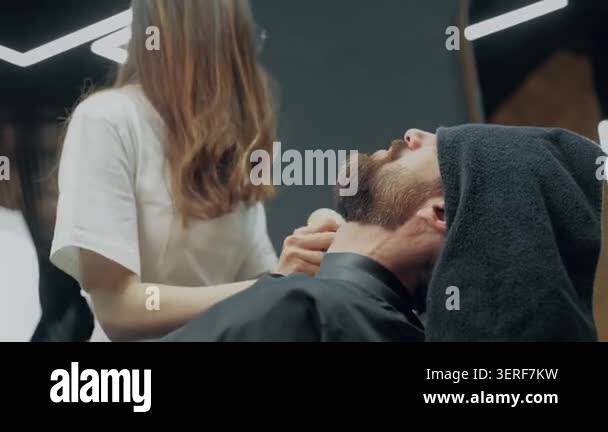 Professional barber using brush to apply talcum powder on beard of ...