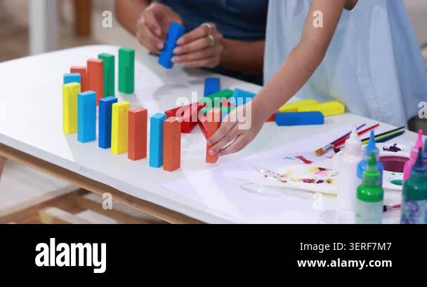 Child and adult playing with colorful wooden blocks at a white table ...