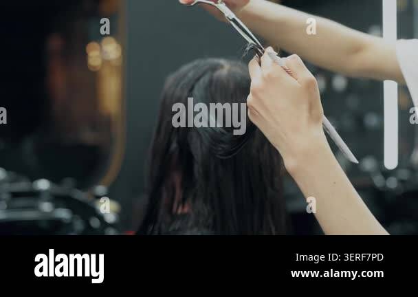 Female barber cutting long wet hair of male client with scissors and ...