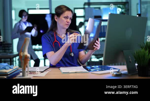 Focused woman doctor looks at x-ray image of patient knee joint in ...