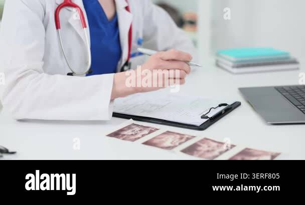 Female doctor writes medical reports on clipboard as sits at clinic ...